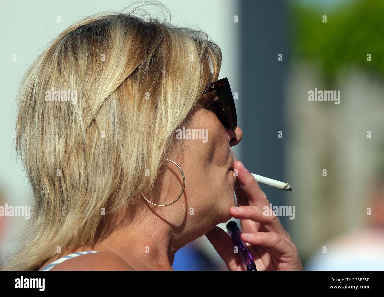 Woman smoking cigarette outdoors in public house grounds Stock Photo ...