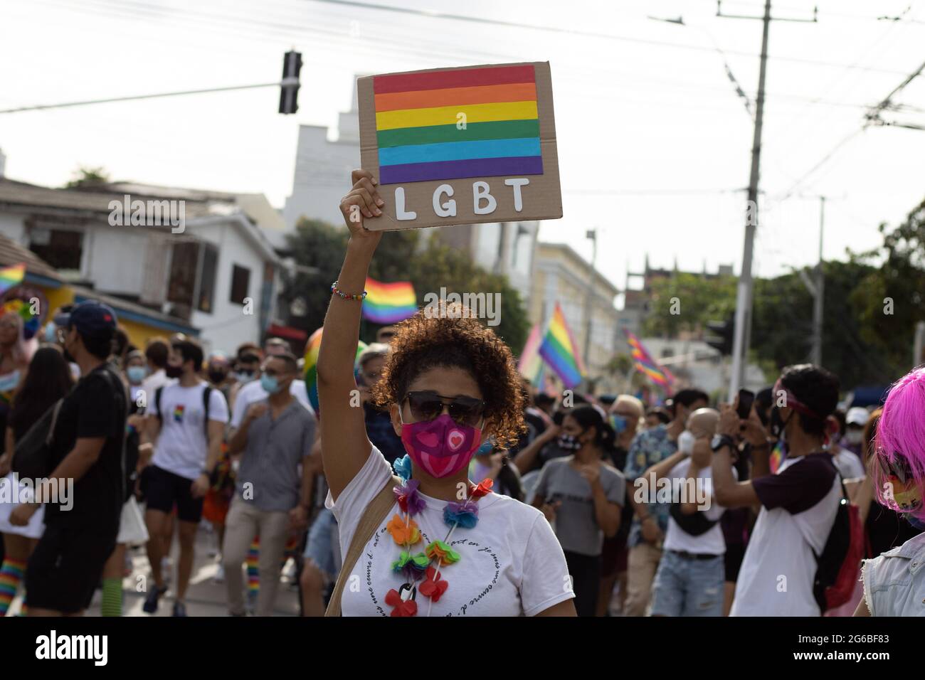 A demonstrator holds a sign that reads "LGBT" and the Pride flag as ...