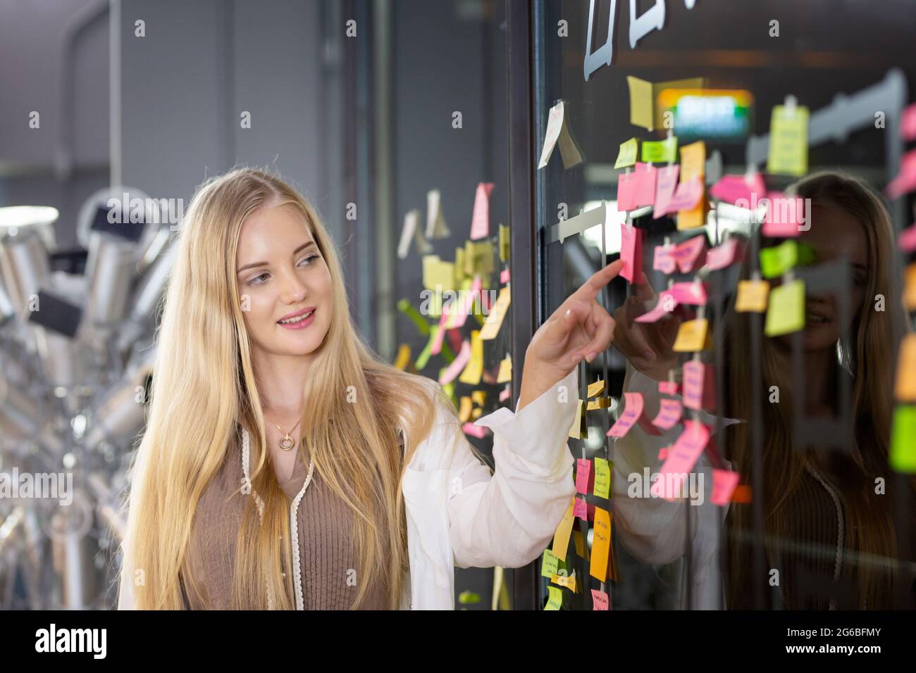 Young women sticking post-its on an idea board. Brainstorming and ...