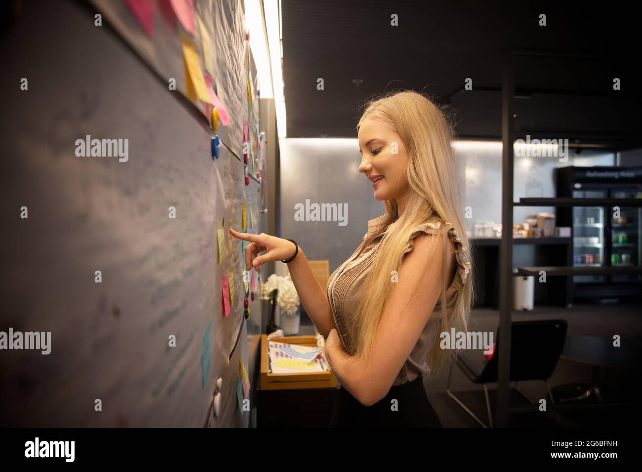 Young women sticking post-its on an idea board. Brainstorming and ...