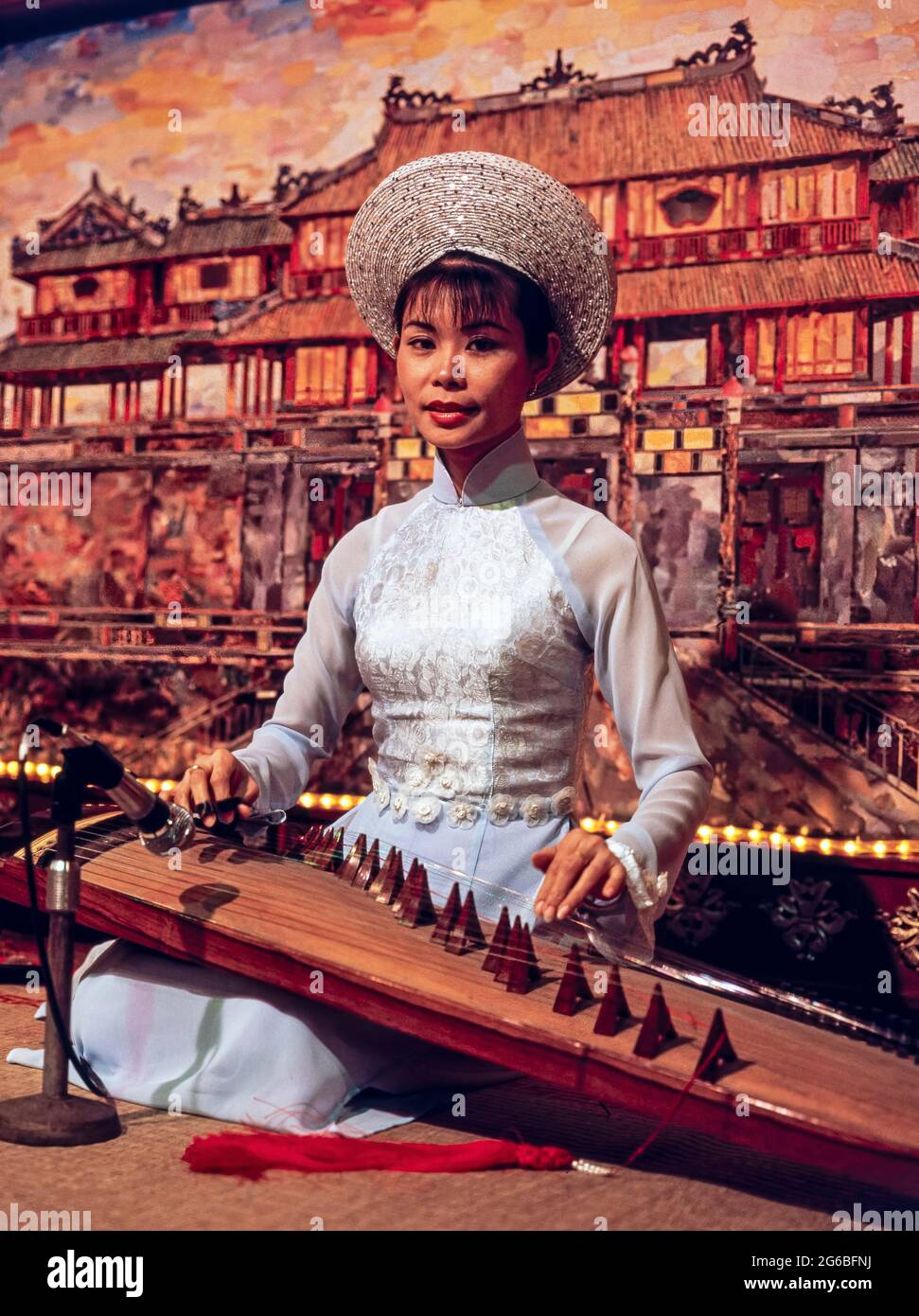 Vietnamese lady in traditional dress playing zither at culture show, Ho ...
