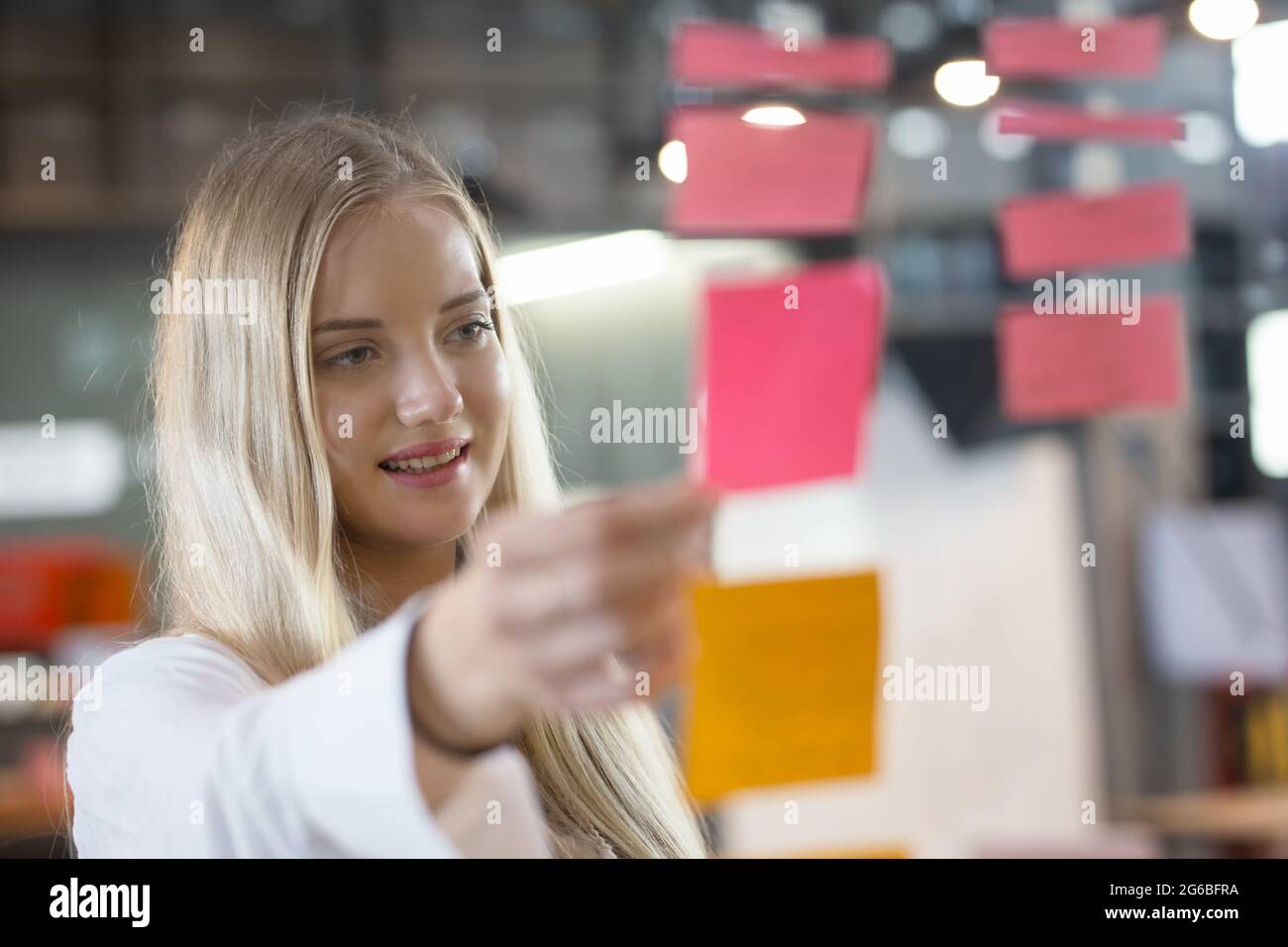 Young women sticking post-its on an idea board. Brainstorming and ...