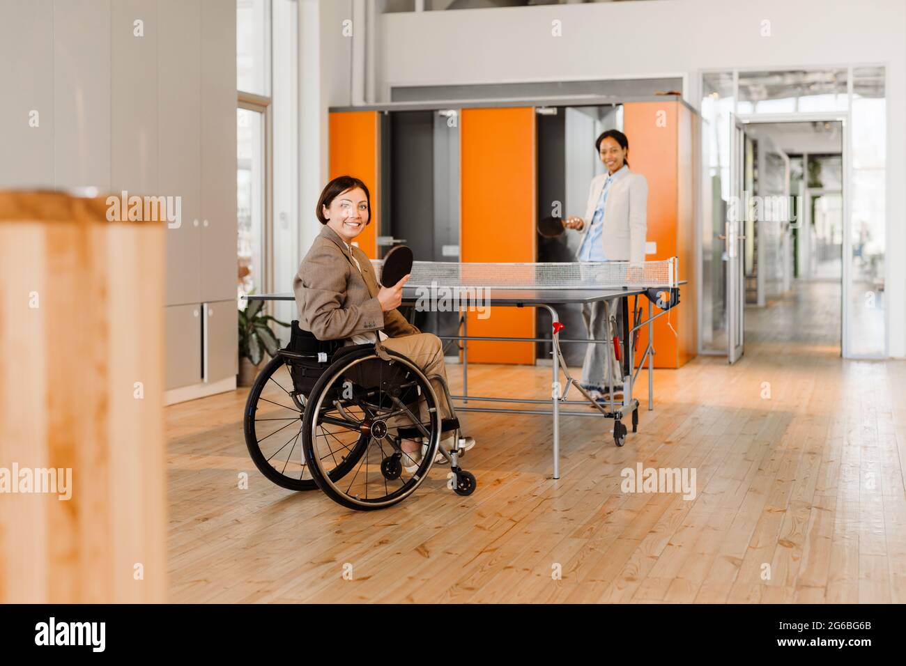 White woman in wheelchair playing ping-pong with her colleague at ...