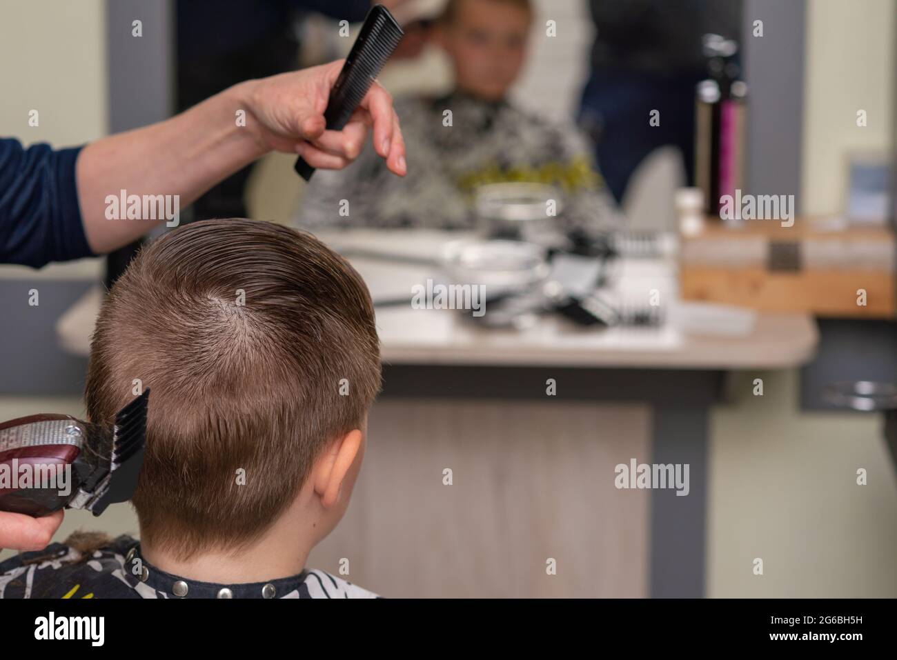 Cute kid boy have hair cut, professional barber doing haircut ...