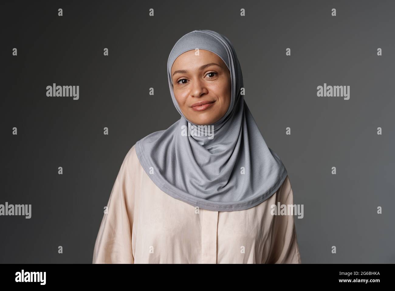 Middle eastern woman in hijab smiling and looking at camera isolated ...