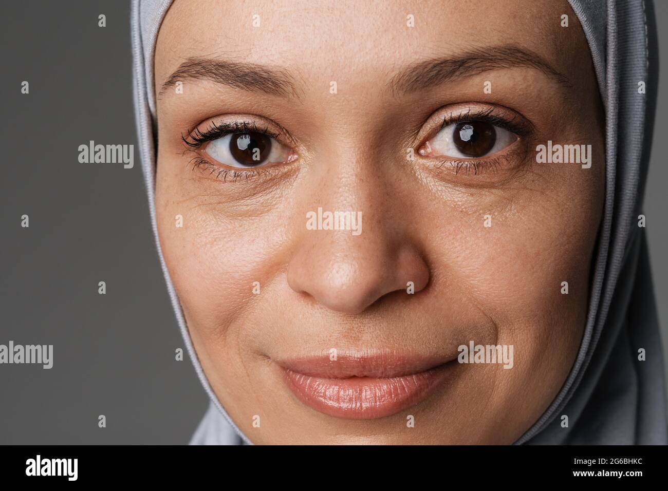 Middle eastern woman in hijab smiling and looking at camera isolated ...