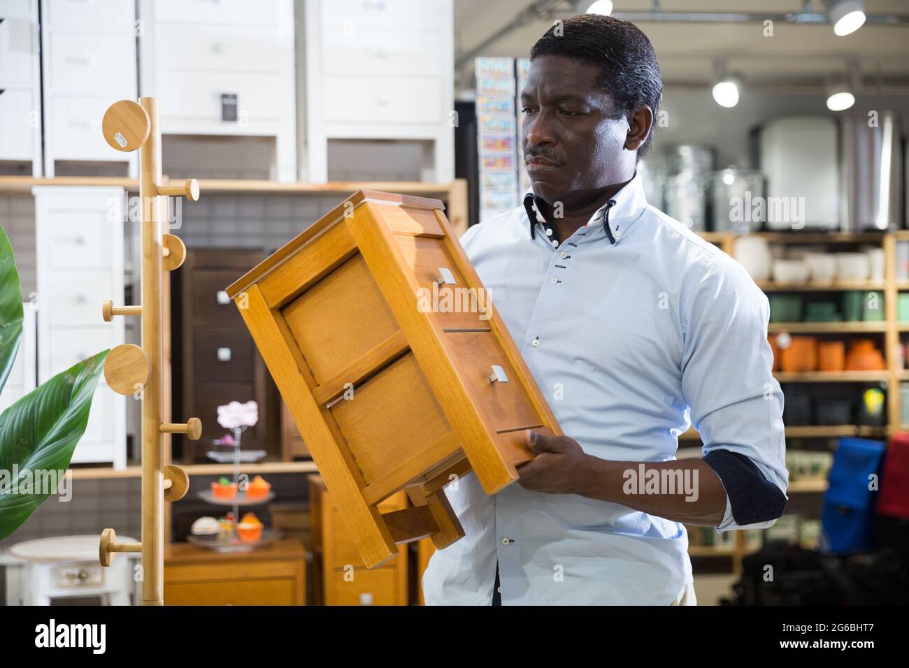 Portrait of man choosing chest of drawers in furniture store Stock ...
