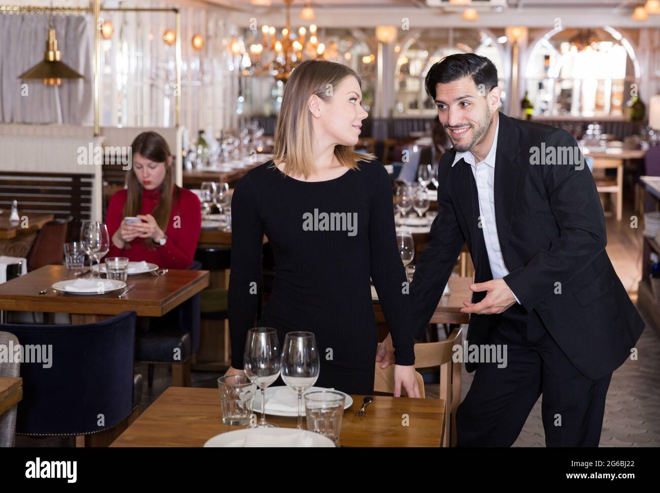 Gentleman helping woman with her chair in restaurant Stock Photo - Alamy