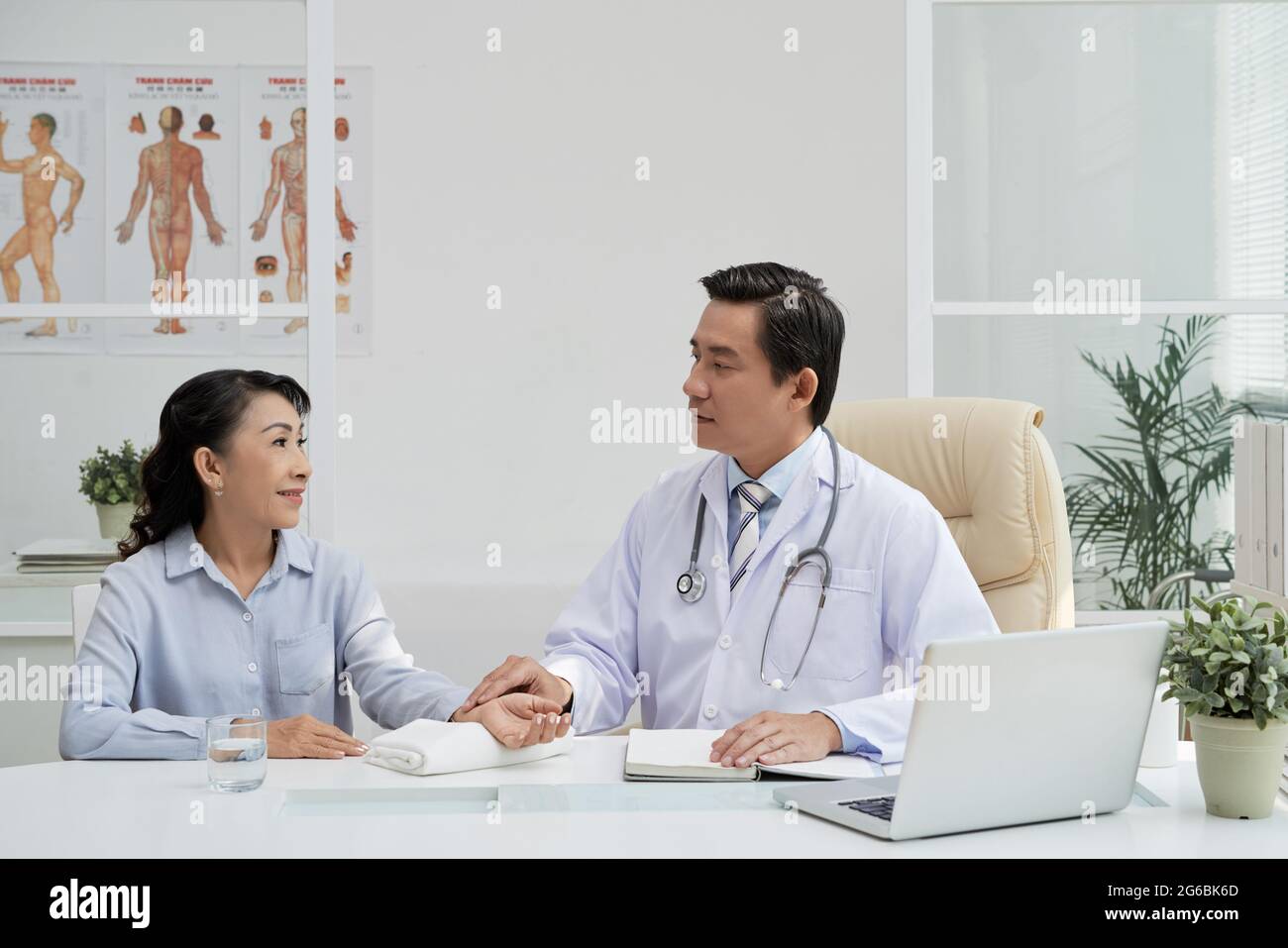 General practitioner talking to senior patient and taking her pulse ...