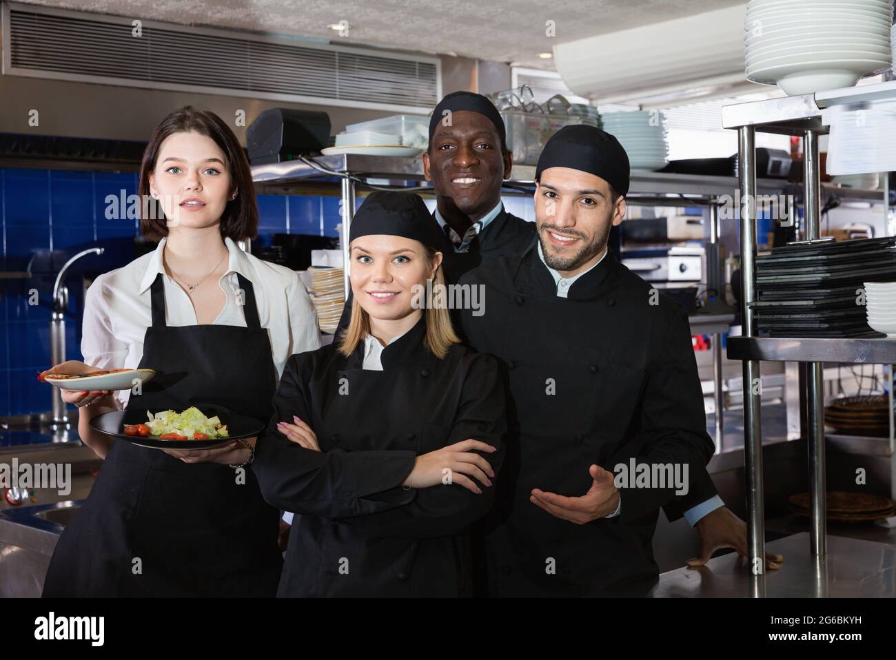 Woman waiter with command of cooks are posing together on kitchen in ...