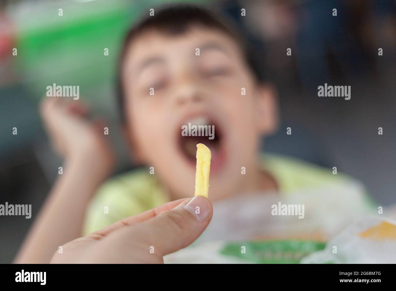 French fries in hand, fast food, in front of a hungry toddler Stock ...
