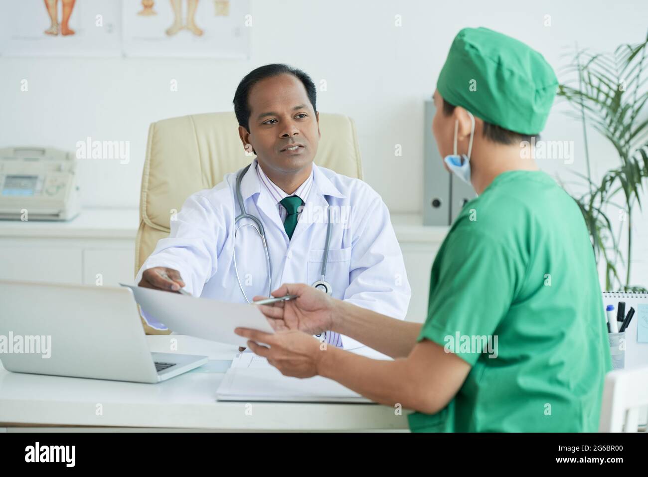 Surgeon showing medical test results of patient to general practitioner ...