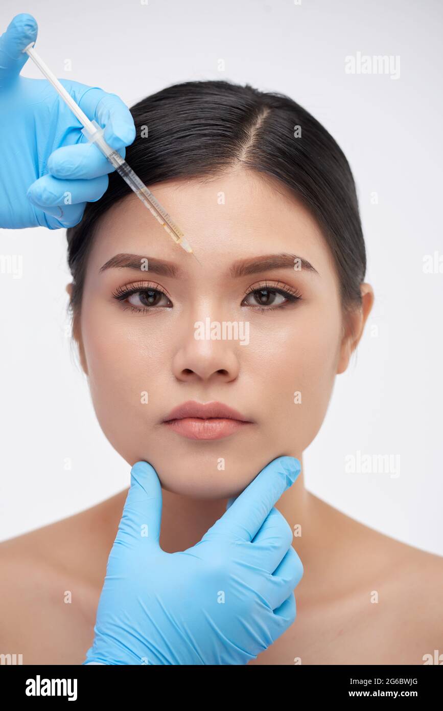 Young woman getting filler injection between her eyebrows to get rid of ...