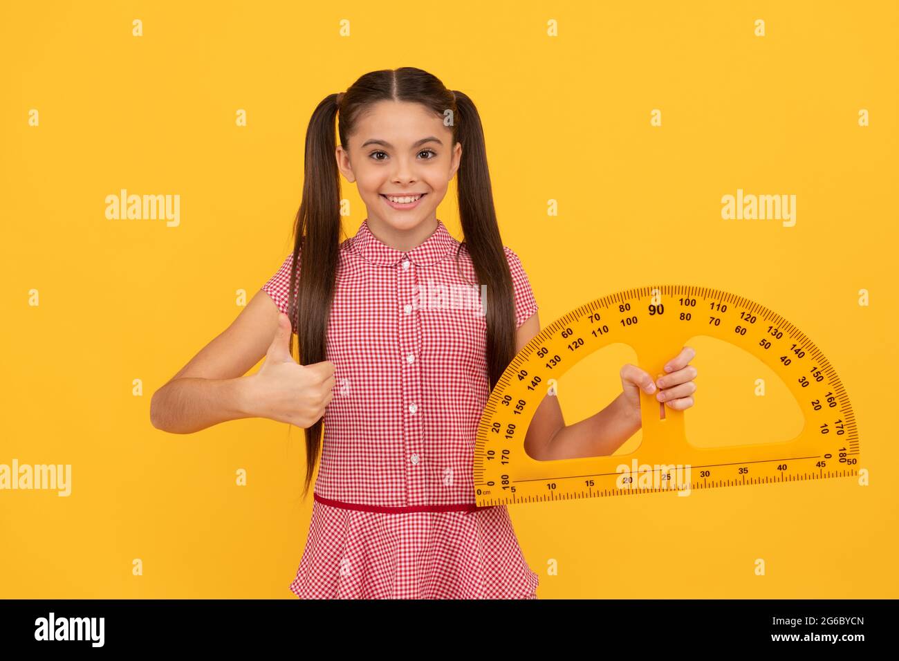 happy child hold school math tool protractor ruler on yellow background ...