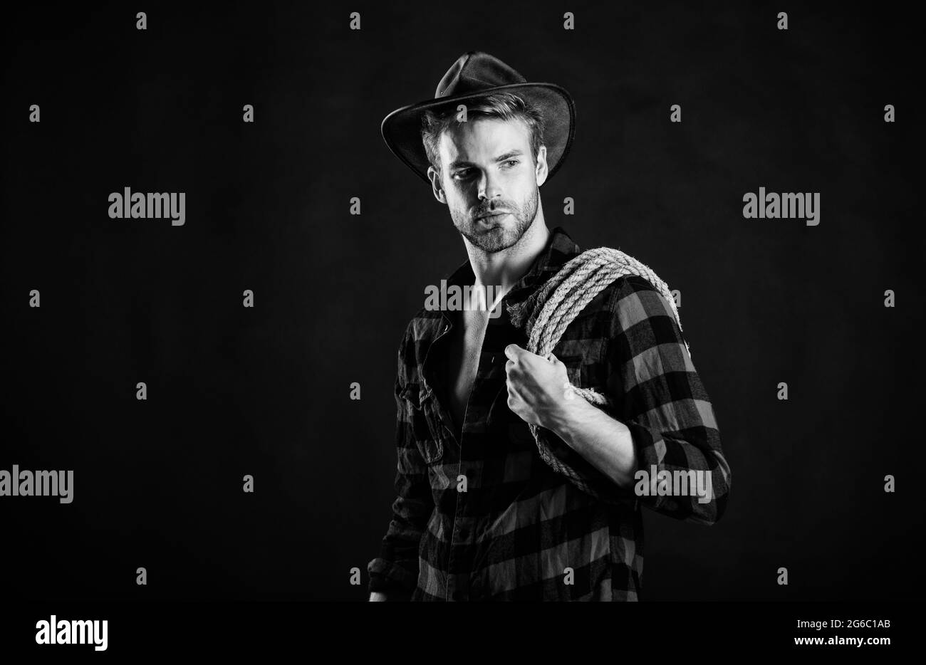 Western life. Lassoing on prairie. Man unshaven cowboy black background ...