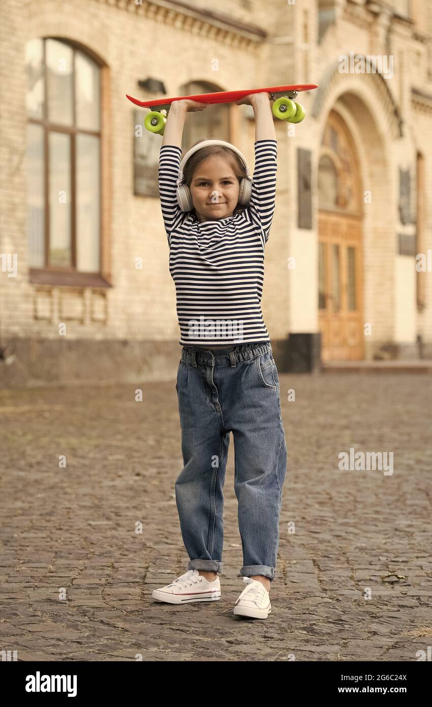 Happy skater girl in headphones raise penny board over head summer ...