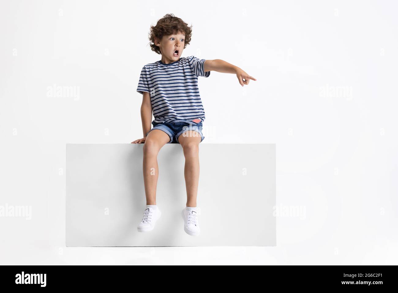 Little Caucasian preschool boy sitting on box isolated over white ...