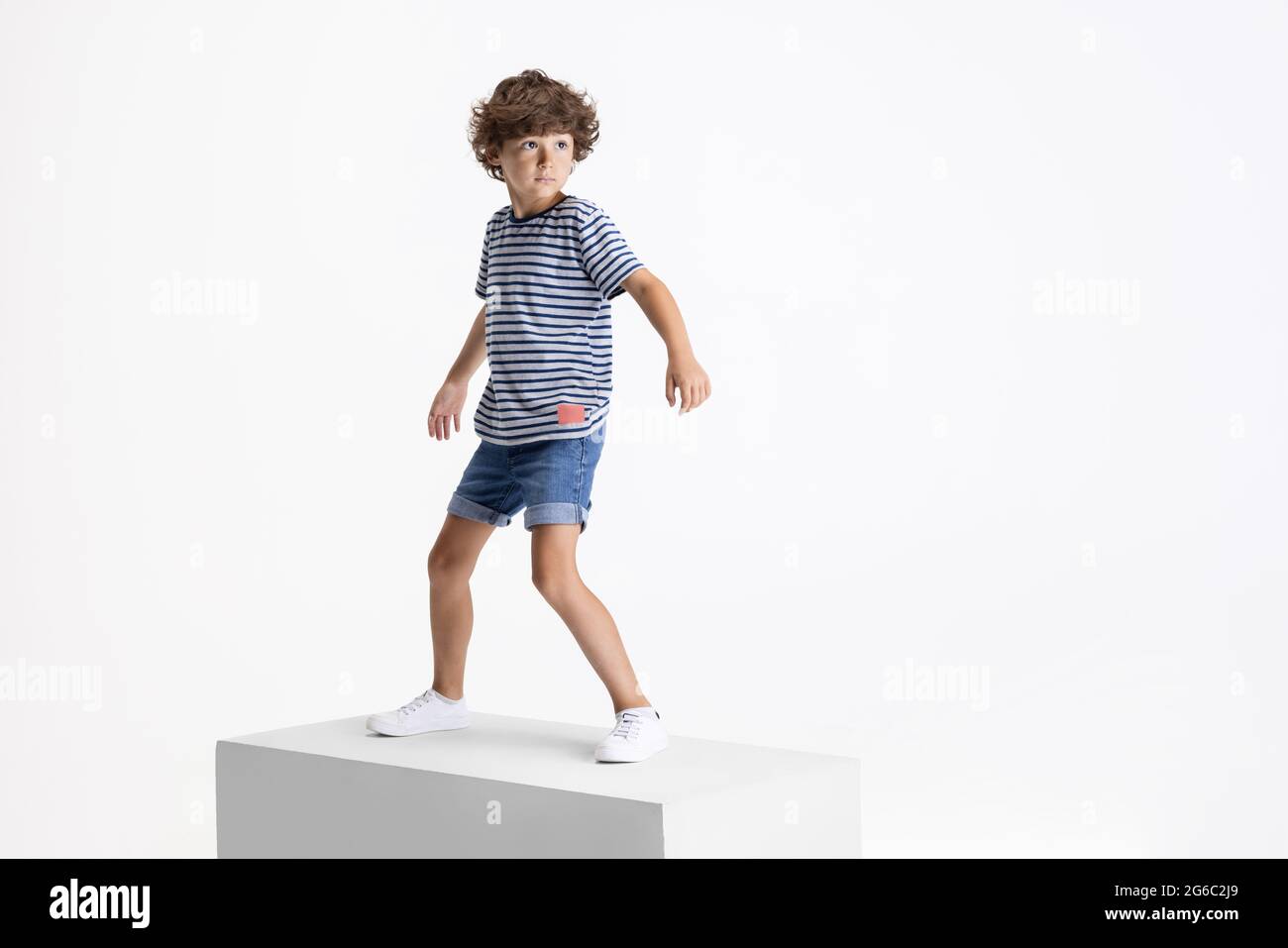 Caucasian preschool boy standing on big box isolated over white studio ...