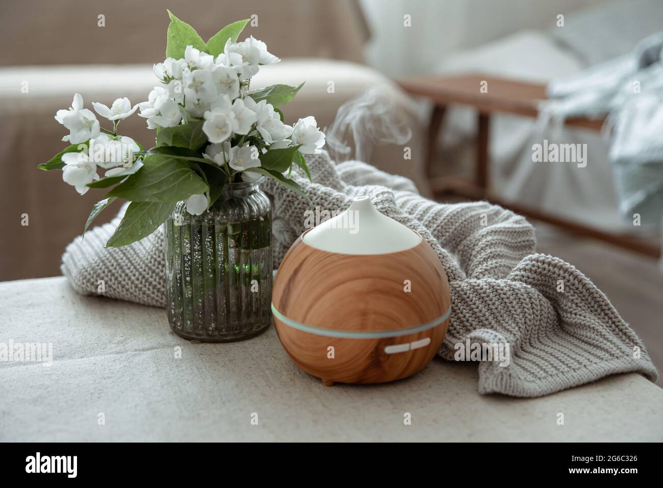 Modern oil aroma diffuser in the living room on the table with knitted ...