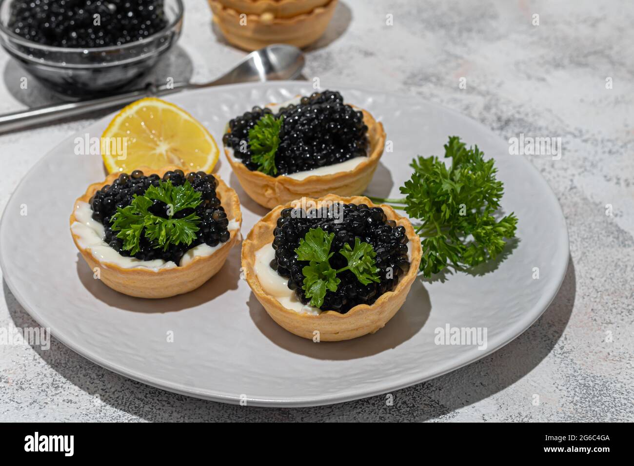 Black caviar in tartlets on a light background. Healthy food concept ...