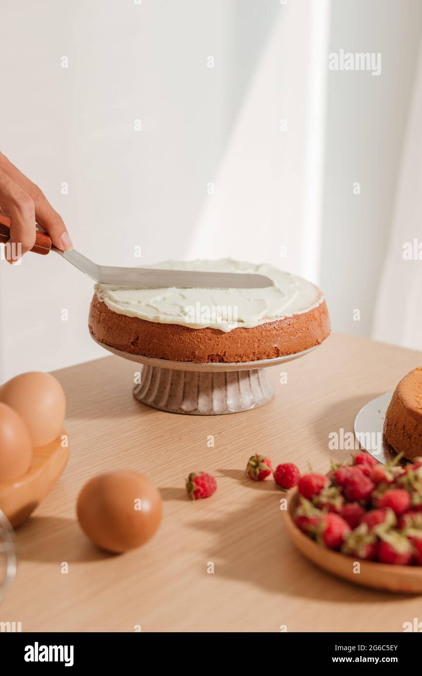 Spreading cream on sponge cake. Making red velvet process Stock Photo ...