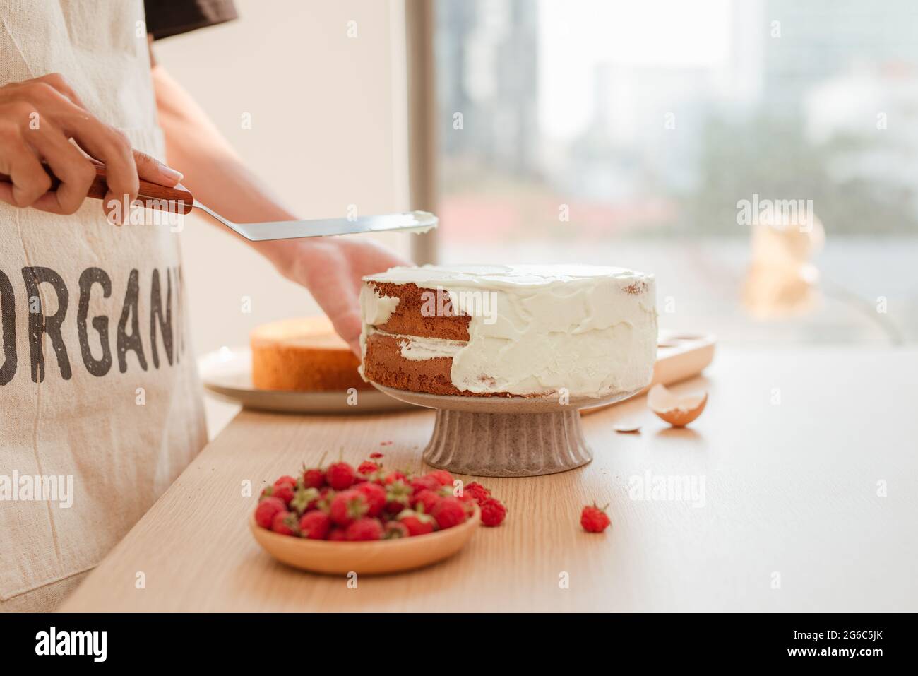 Man hand put whipped cream on the sponge cake. Making sponge cake ...