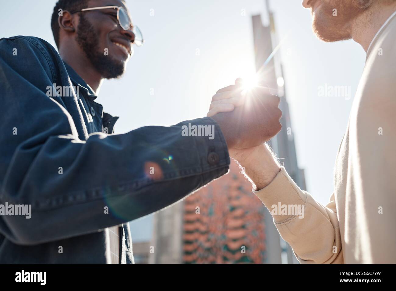 Side view close up of two men shaking hands while greeting each other ...