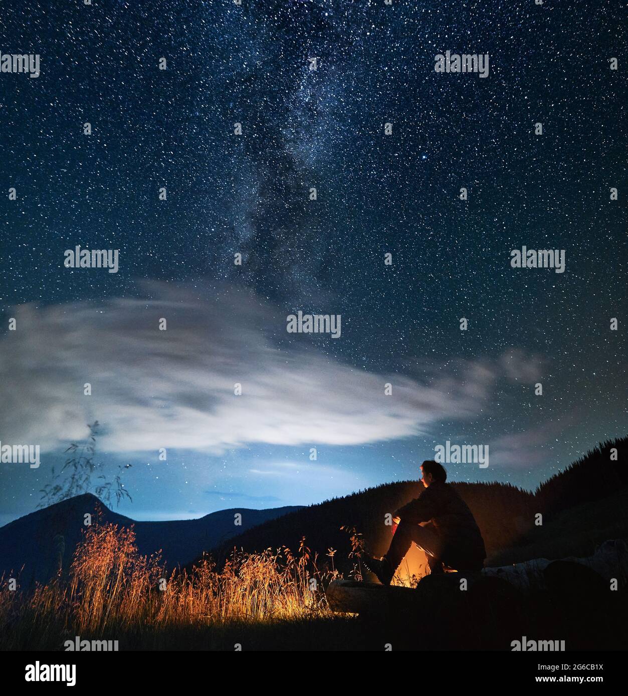 Side view of silhouette of man relaxing near forest and watching night ...