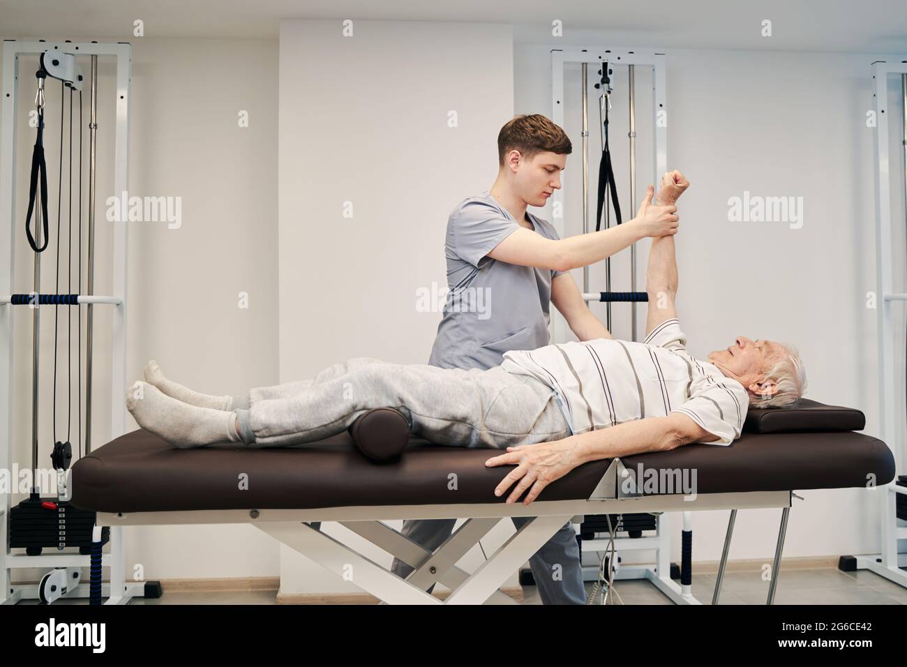 Orthopedist helping old man on couch in raising right arm Stock Photo ...