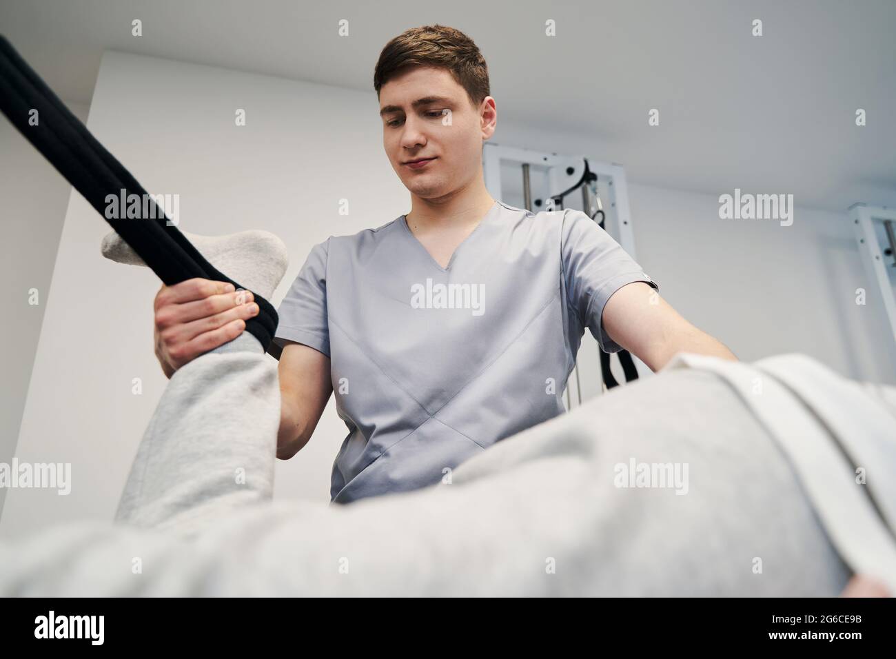 Medical person attaching ankle strap to patient leg Stock Photo - Alamy