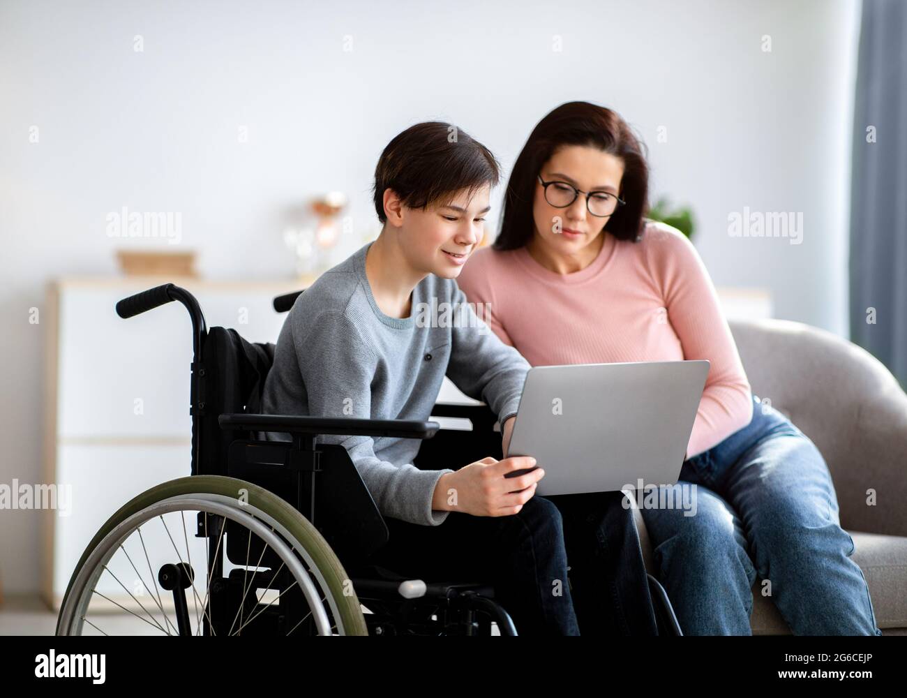 Remote education concept. Cheerful disabled teenager in wheelchair ...