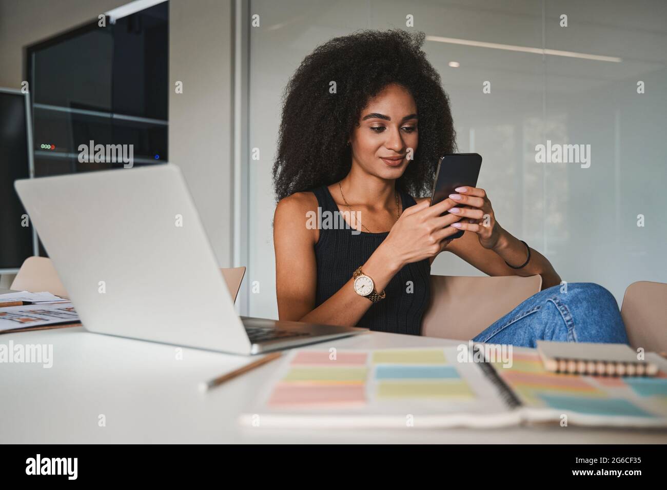 Calm office worker using her smartphone and smiling Stock Photo - Alamy