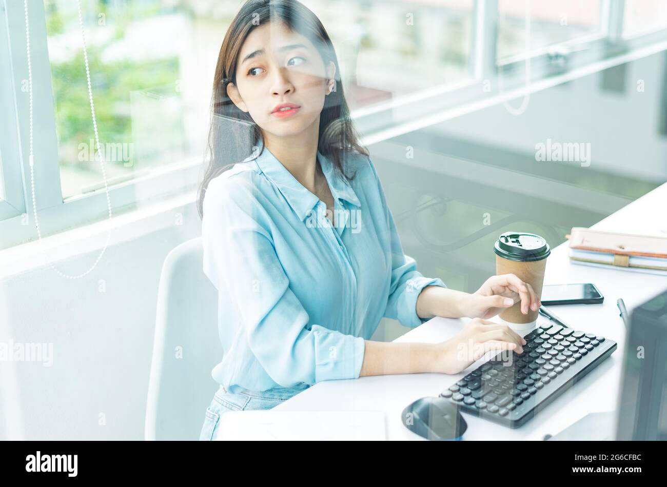 Portrait of young business woman working and looking out the window ...
