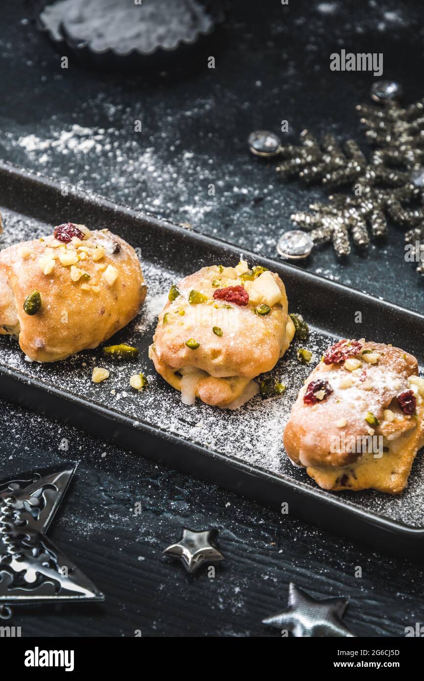 Homemade mini stollen with icing, dried cranberries and pistachios on a ...