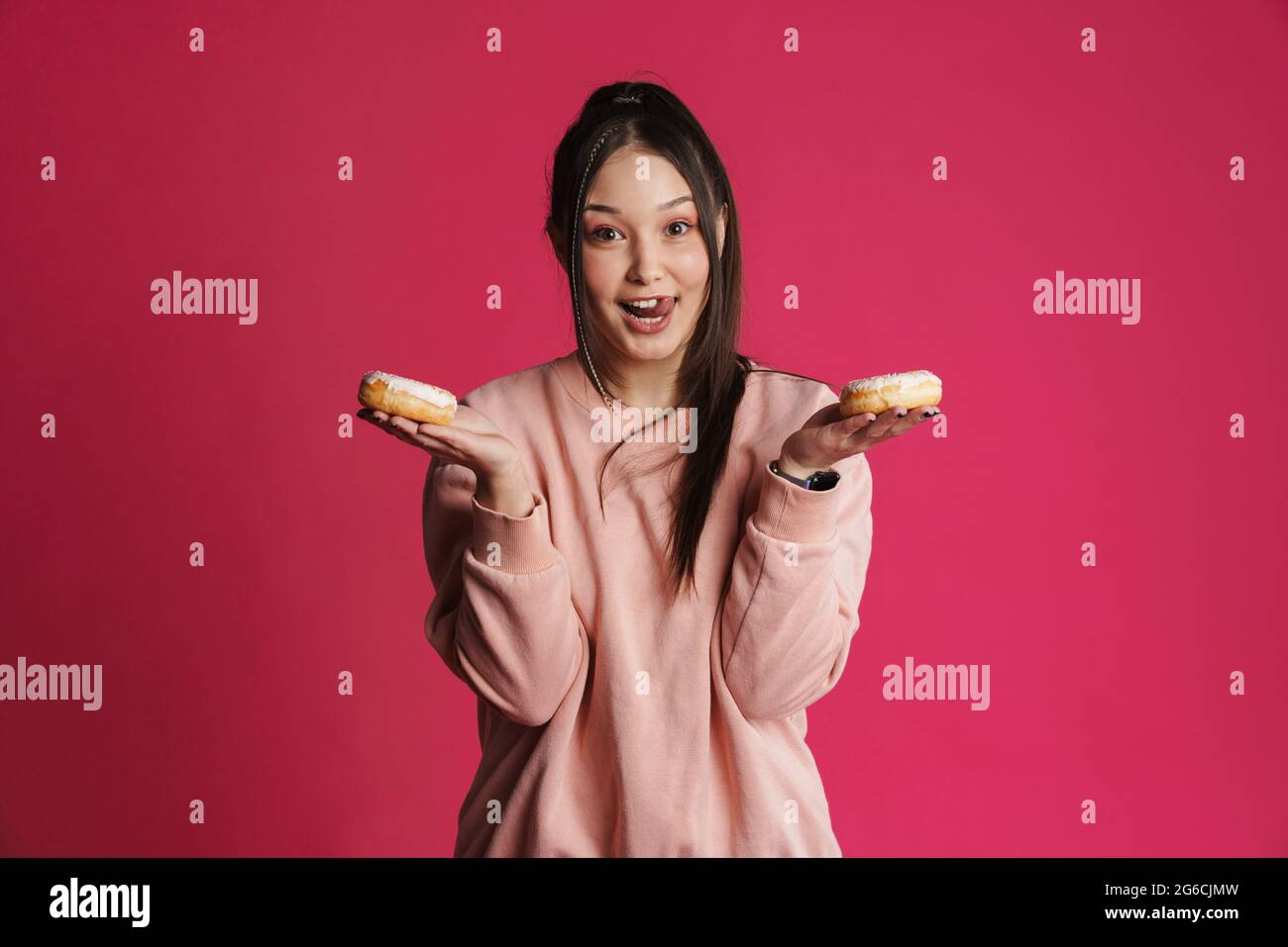 Asian happy woman showing her tongue while posing with donuts isolated ...