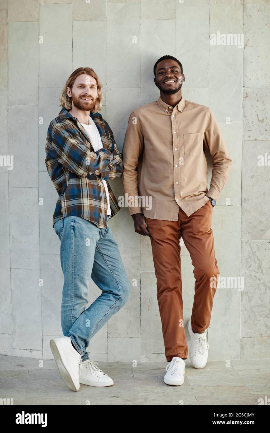 Minimal full length portrait of two young men posing and smiling at ...