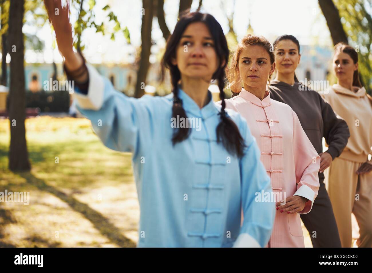 Tai chi coach raising arm while students standing behind her Stock ...