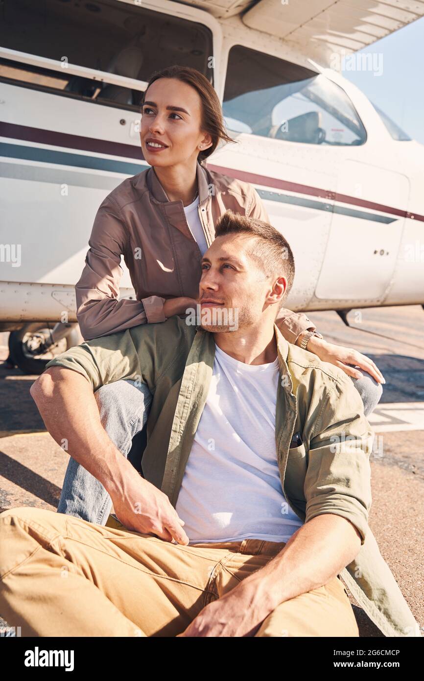 Beautiful loving couple sitting near aircraft at airfield Stock Photo ...