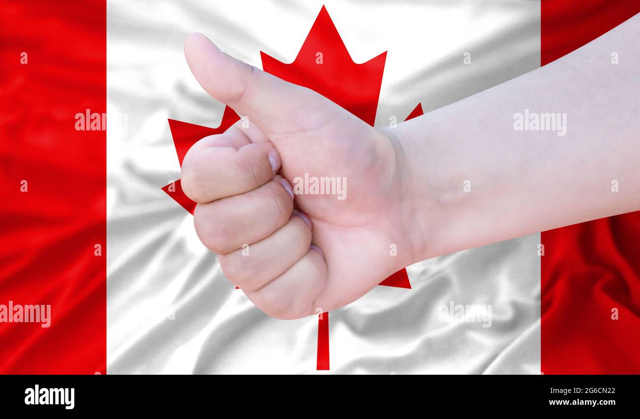 Hand makes a thumbs up sign on the background of the flag of Canada ...