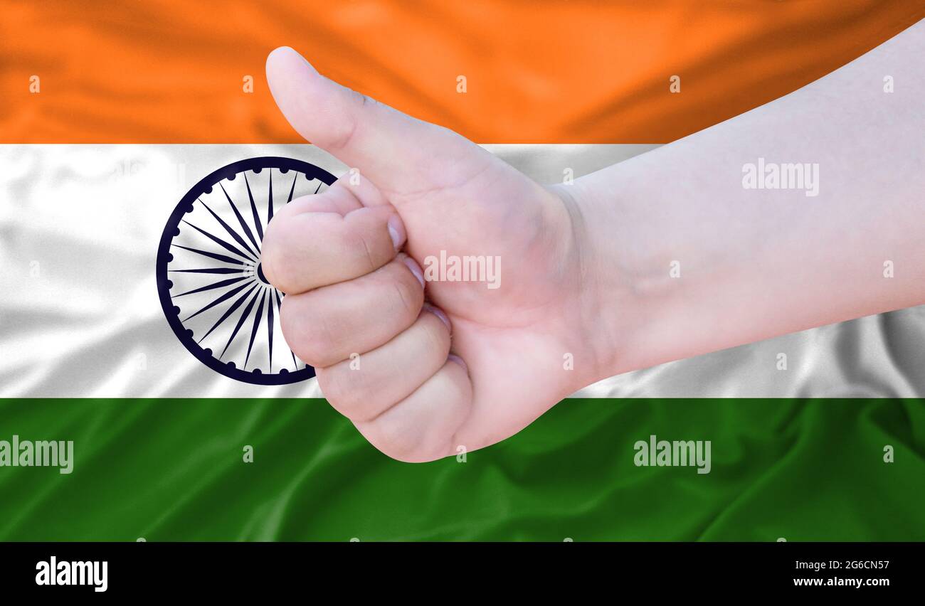 Hand makes a thumbs up sign on the background of the flag of India ...