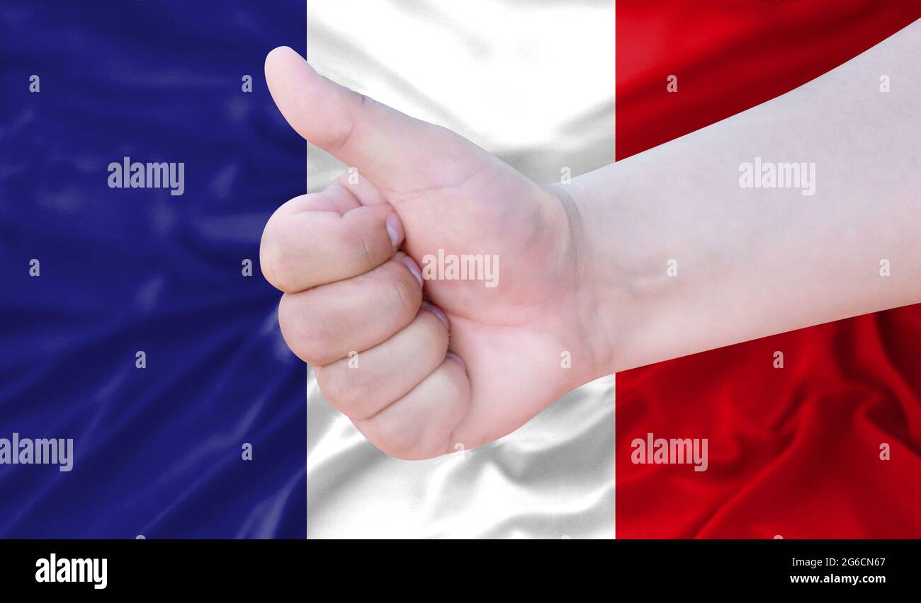 Hand makes a thumbs up sign on the background of the flag of France ...