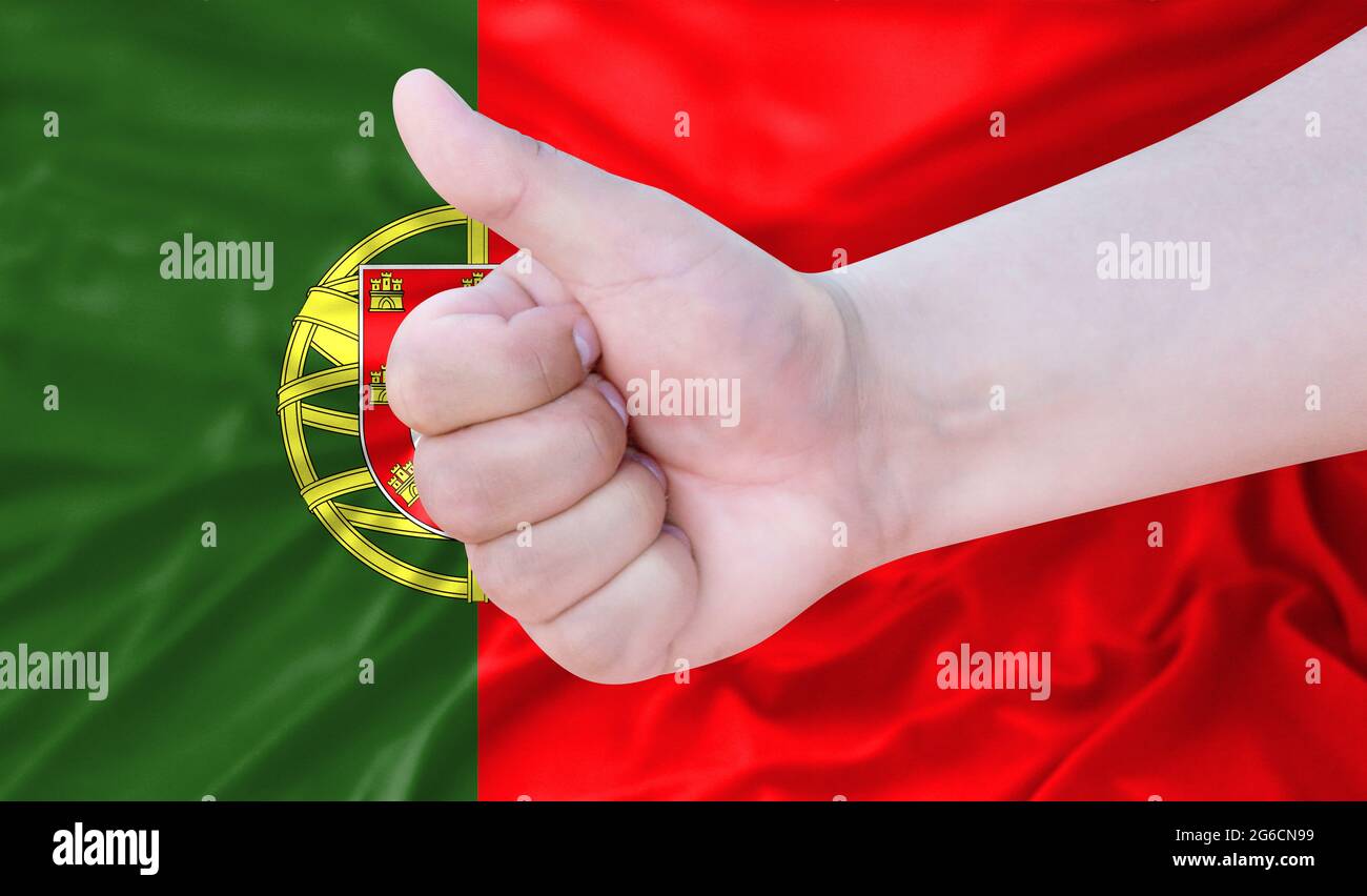 Hand makes a thumbs up sign on the background of the flag of Portugal ...
