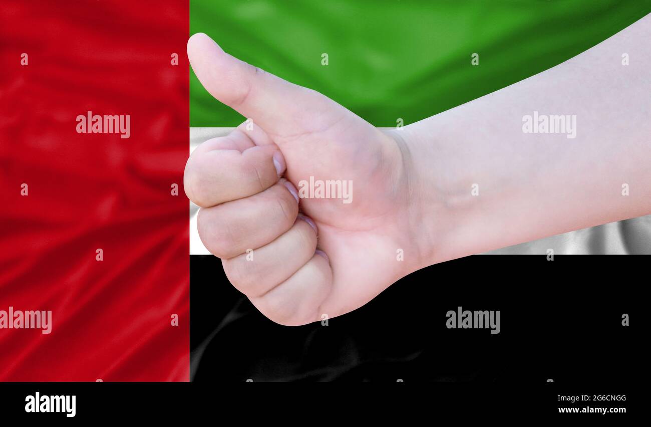 Hand makes a thumbs up sign on the background of the flag of United ...