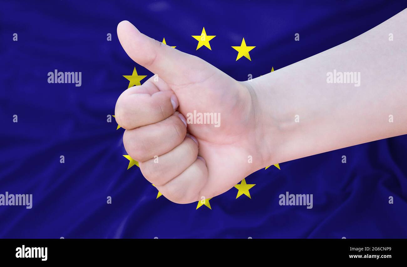 Hand makes a thumbs up sign on the background of the flag of European ...