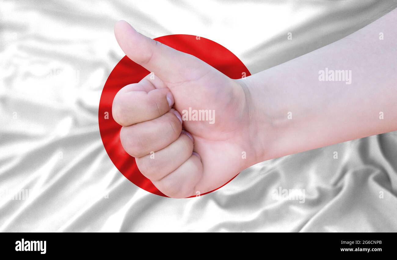 Hand makes a thumbs up sign on the background of the flag of Japan ...