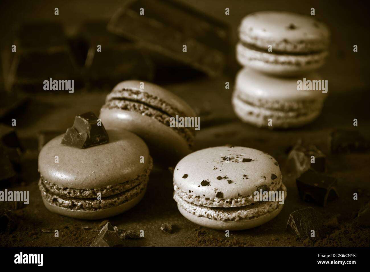Brown and cream colored french macarons with dark chocolate on dark ...
