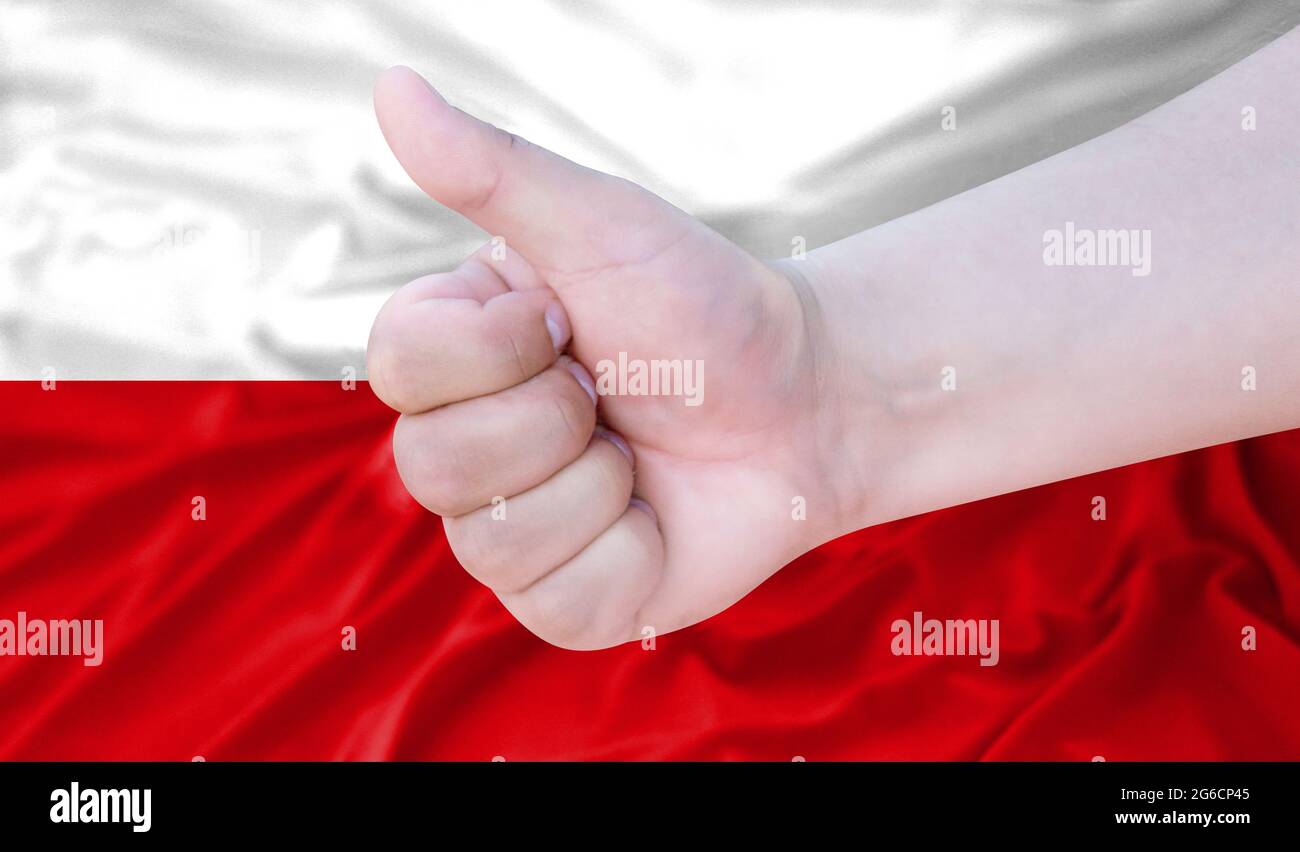Hand makes a thumbs up sign on the background of the flag of Poland ...