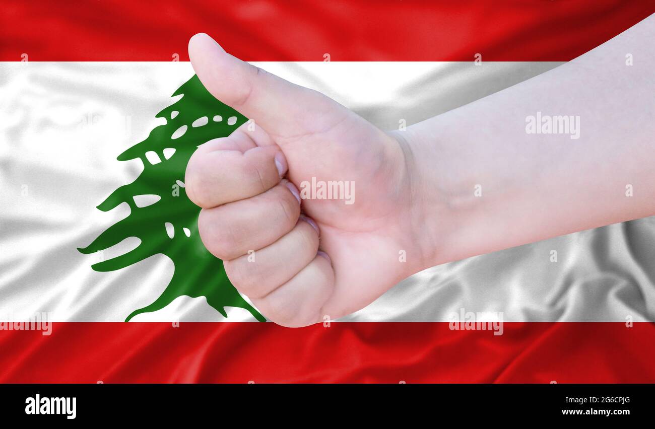Hand makes a thumbs up sign on the background of the flag of Lebanon ...