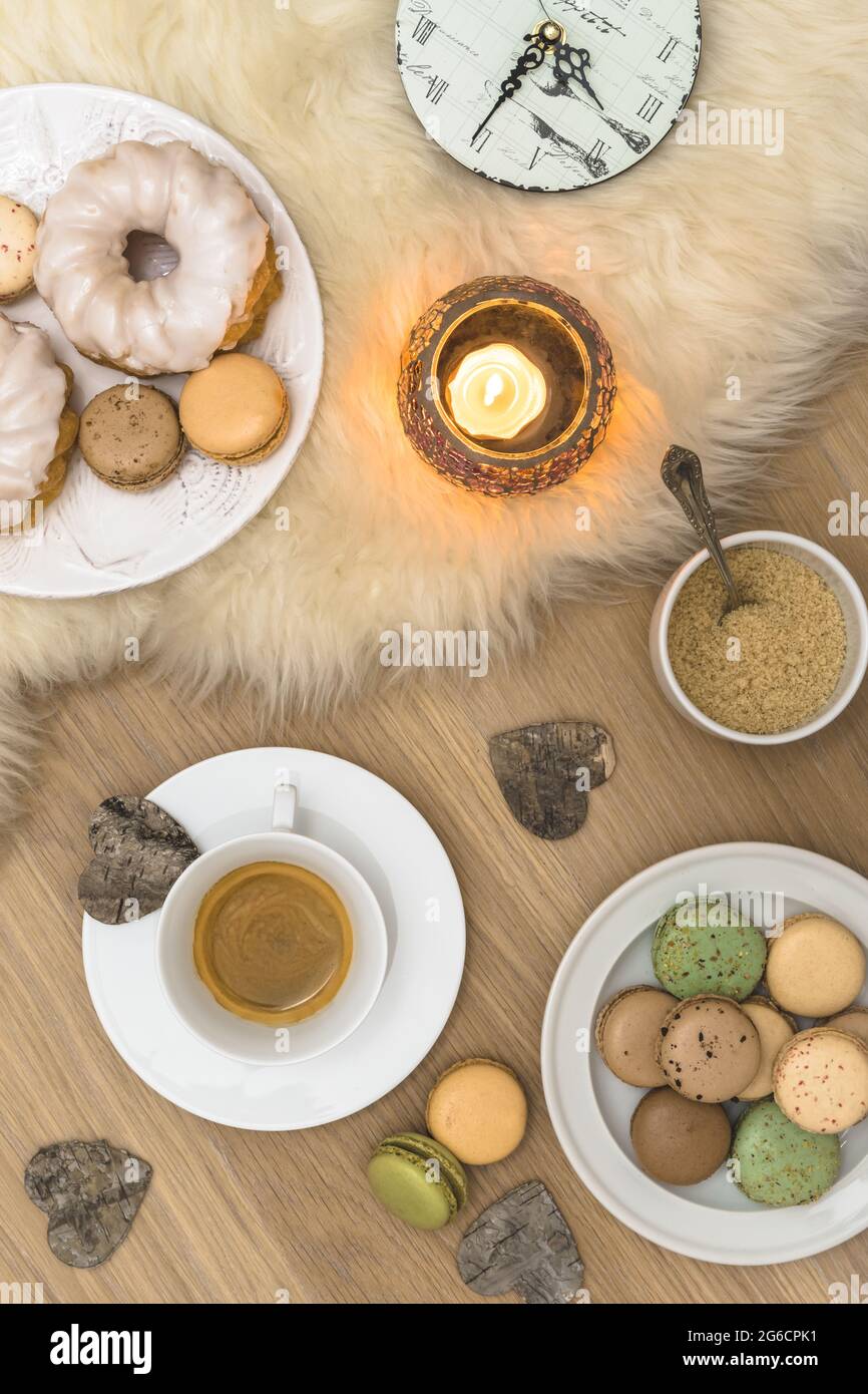 Scene of a cozy coffee break with macarons, donuts, biscuits and candle ...