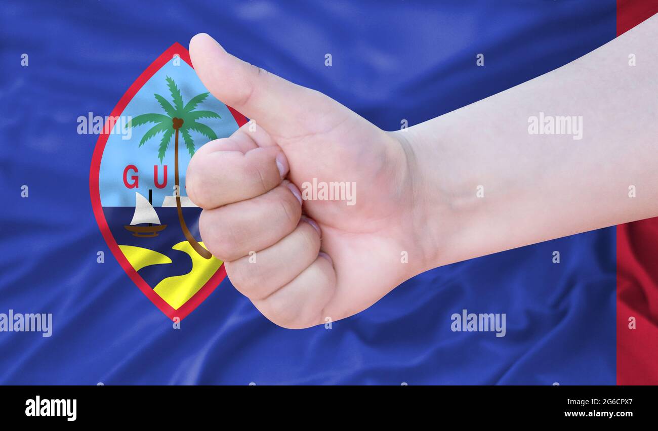 Hand makes a thumbs up sign on the background of the flag of Guam. like ...